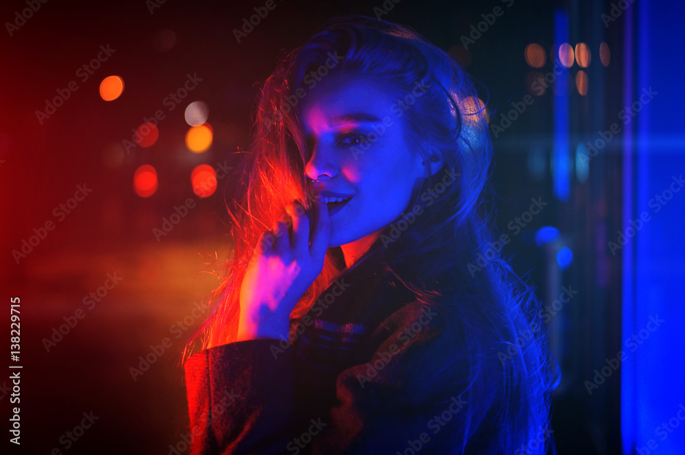 Sexy young beauty woman posing over night city dramatic red and blue ...