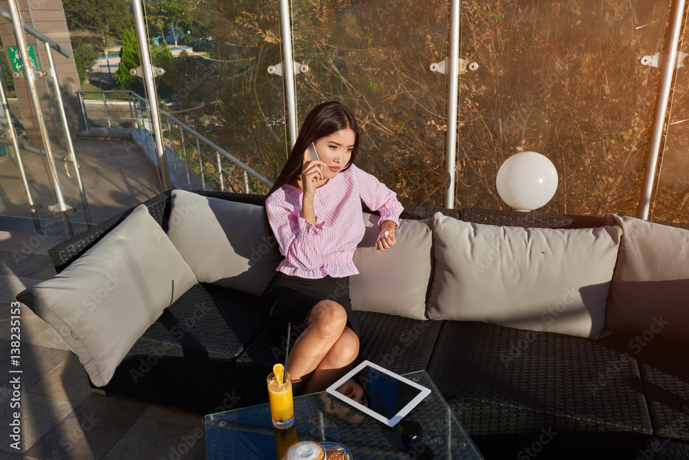 Young charming woman calling with cell telephone while sitting alone in ...