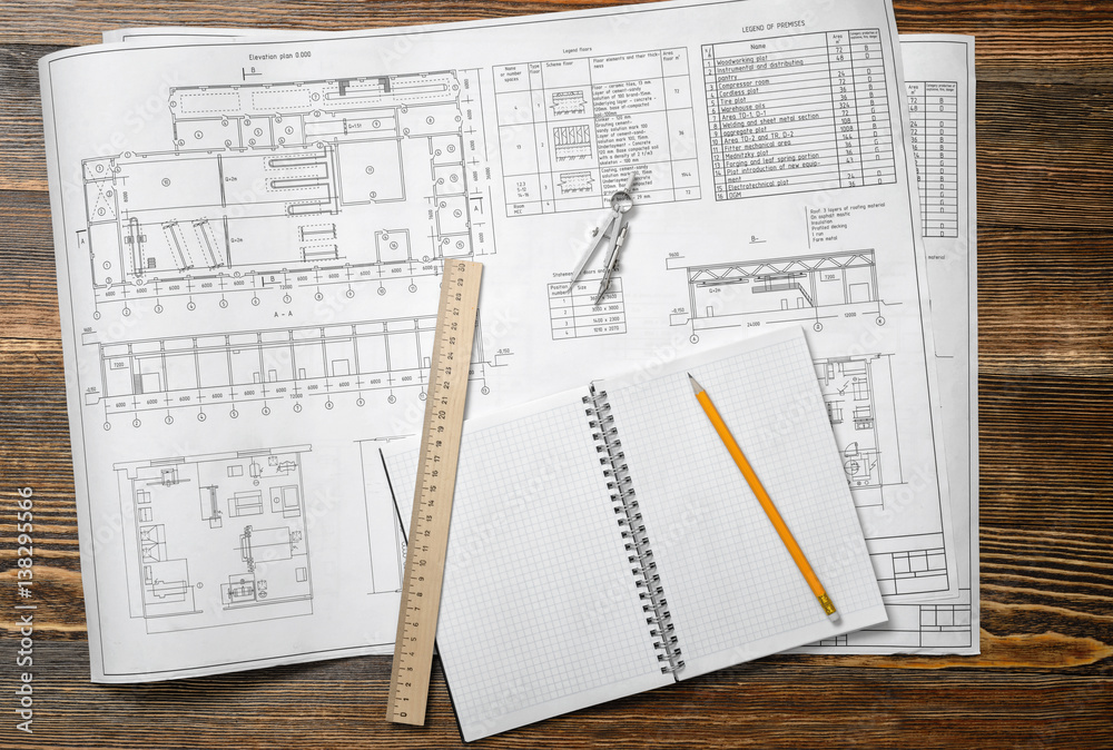 Open blueprints on wooden table background with a pencil, a ruler and ...