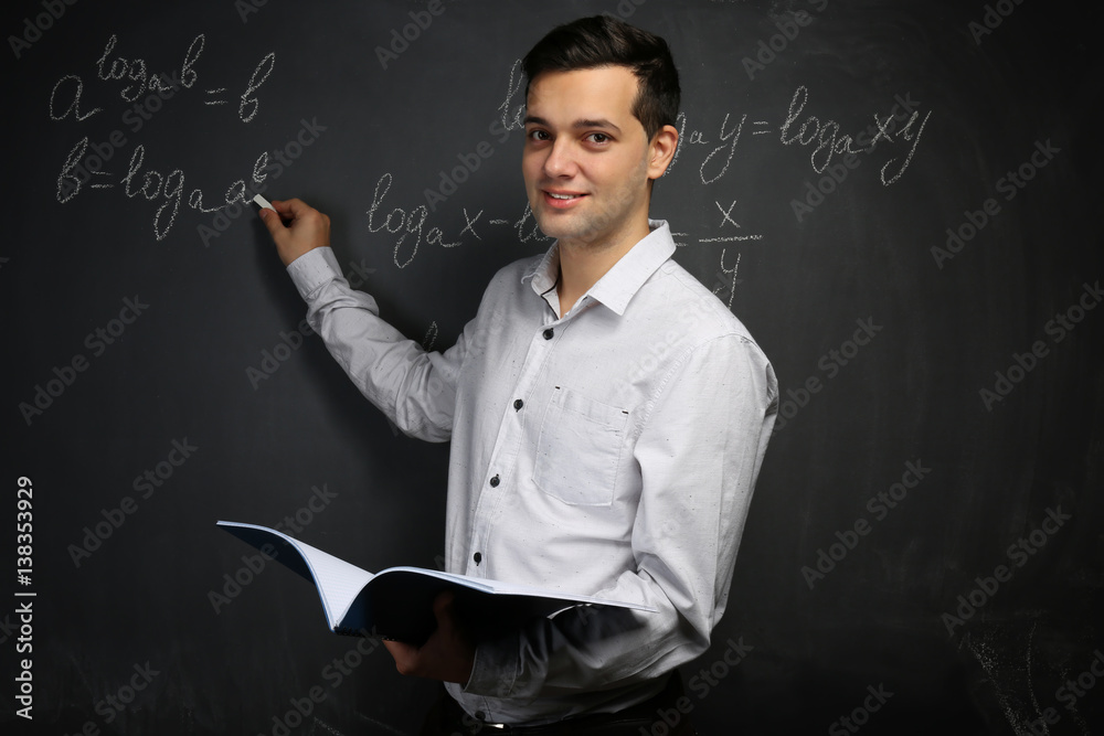 Handsome young teacher writing math formulas on blackboard Stock Photo ...
