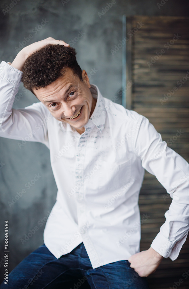 Man in white shirt rubs back of his head looking happy Stock Photo ...