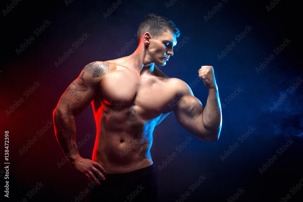 Handsome power athletic man bodybuilder. Fitness muscular body on dark ...