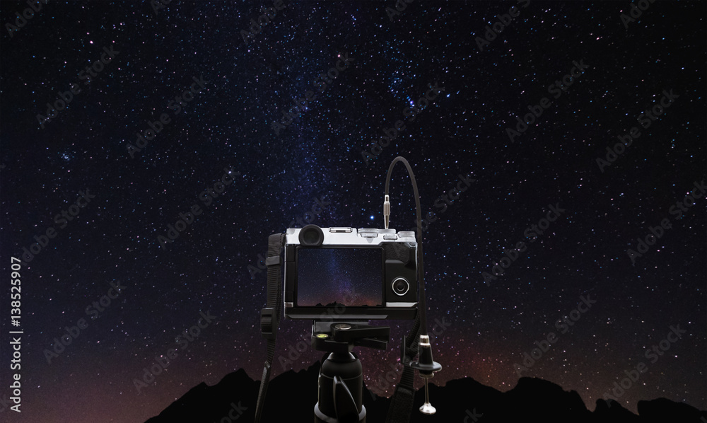 Digital camera on camera tripod taking a photo of milky way at night ...