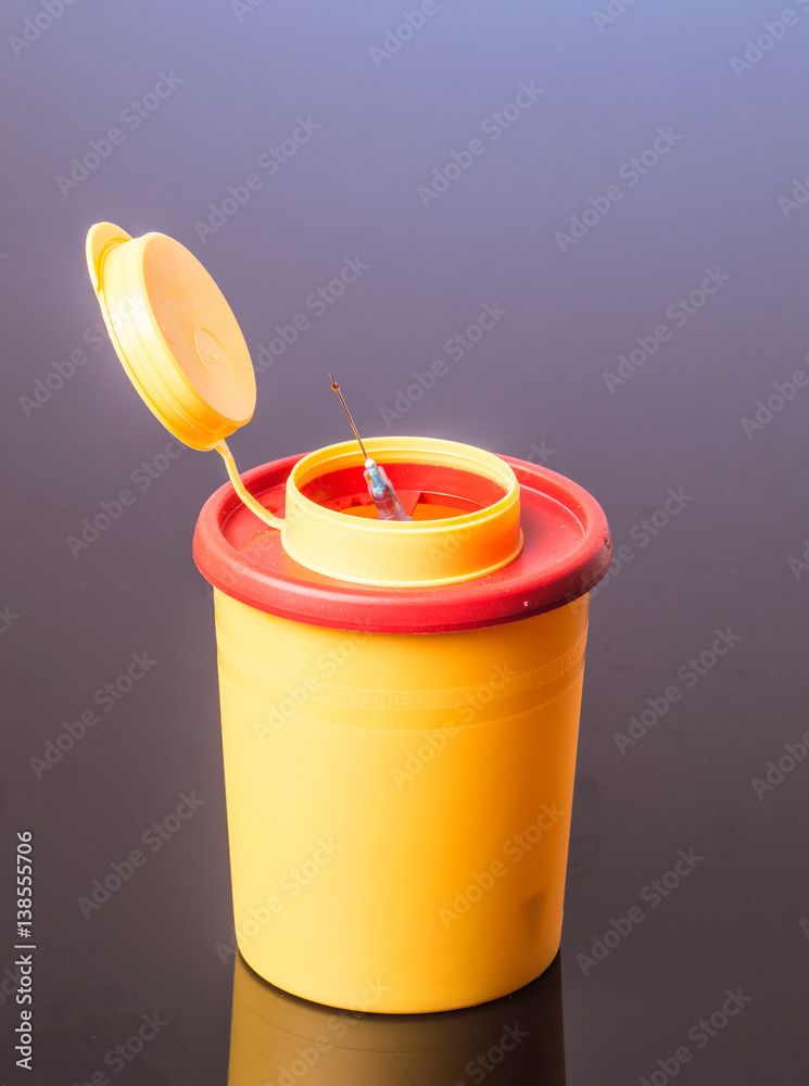 Yellow medical disposal waste box, syringe needle with red drop on the ...