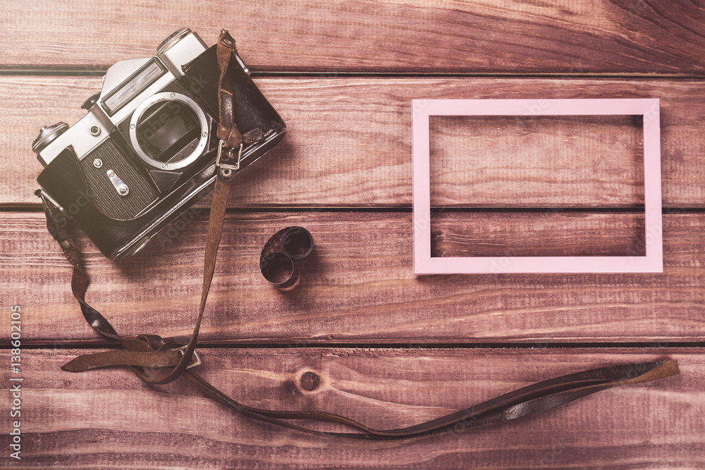 Old film camera with strap, photo frame and film on wooden background ...
