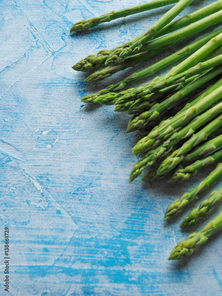 Green asparagus is scattered on a blue background Stock Photo | Adobe Stock