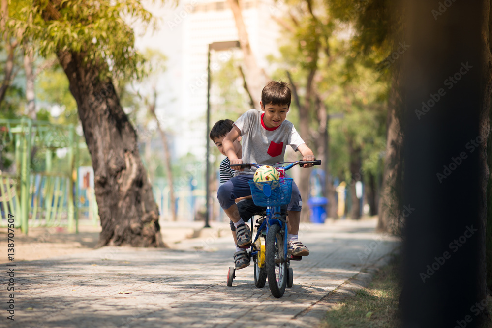 Little sibling boy riding bike together in the park Stock Photo | Adobe ...