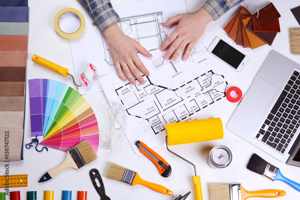 Decorator's hands on project drawing. Laptop, color swatches and tools ...