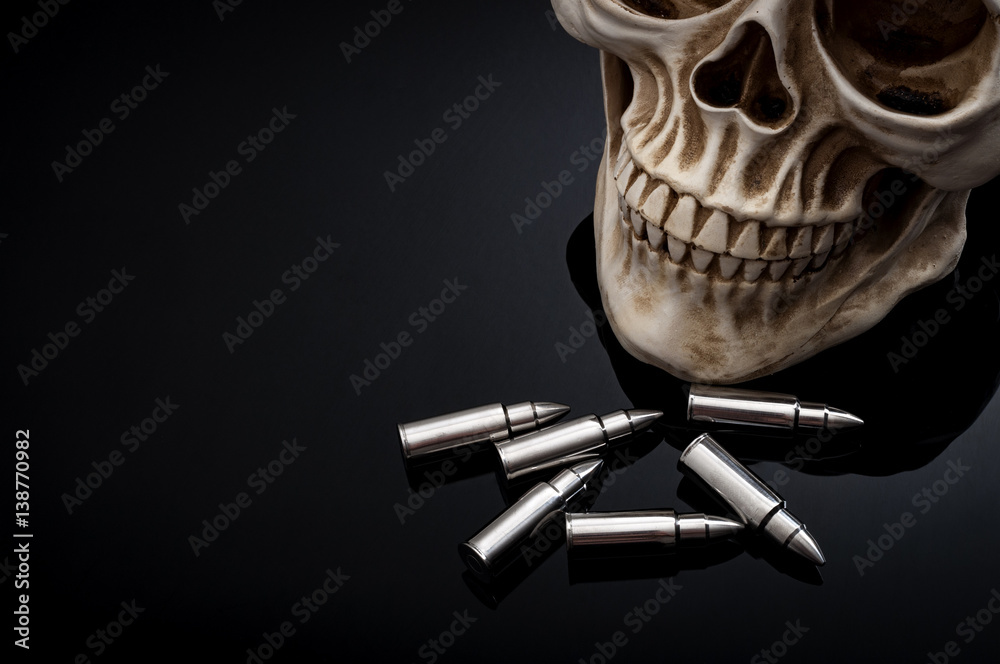 Gun violence and death concept with human skull and scattered bullets ...