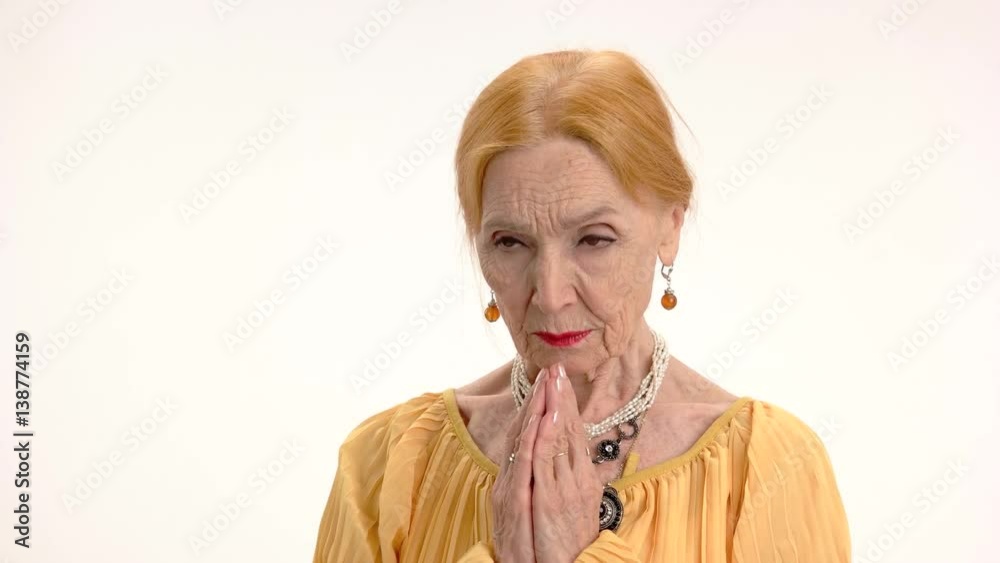 Senior woman praying isolated. Old lady looking down. God forgive me ...