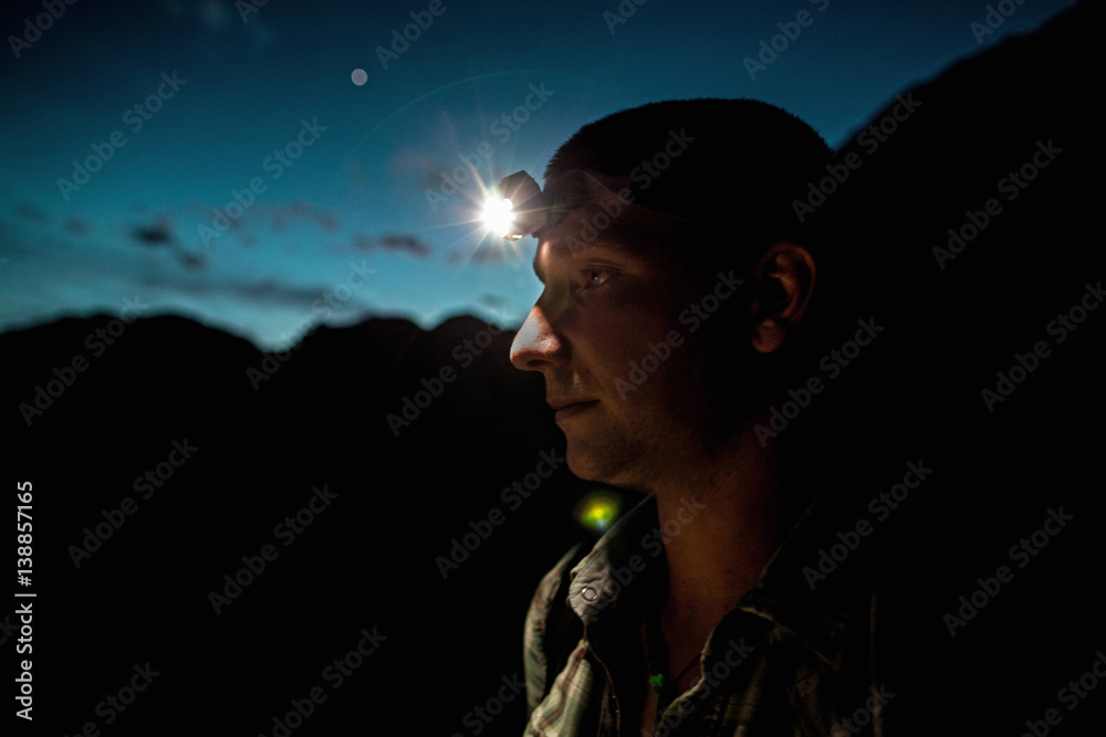 Man wearing lit head torch at night, close up Stock Photo | Adobe Stock
