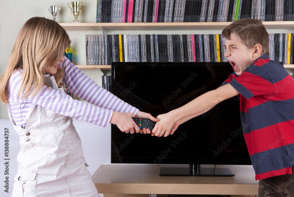 Siblings fighting over the remote control in front of the TV Stock ...
