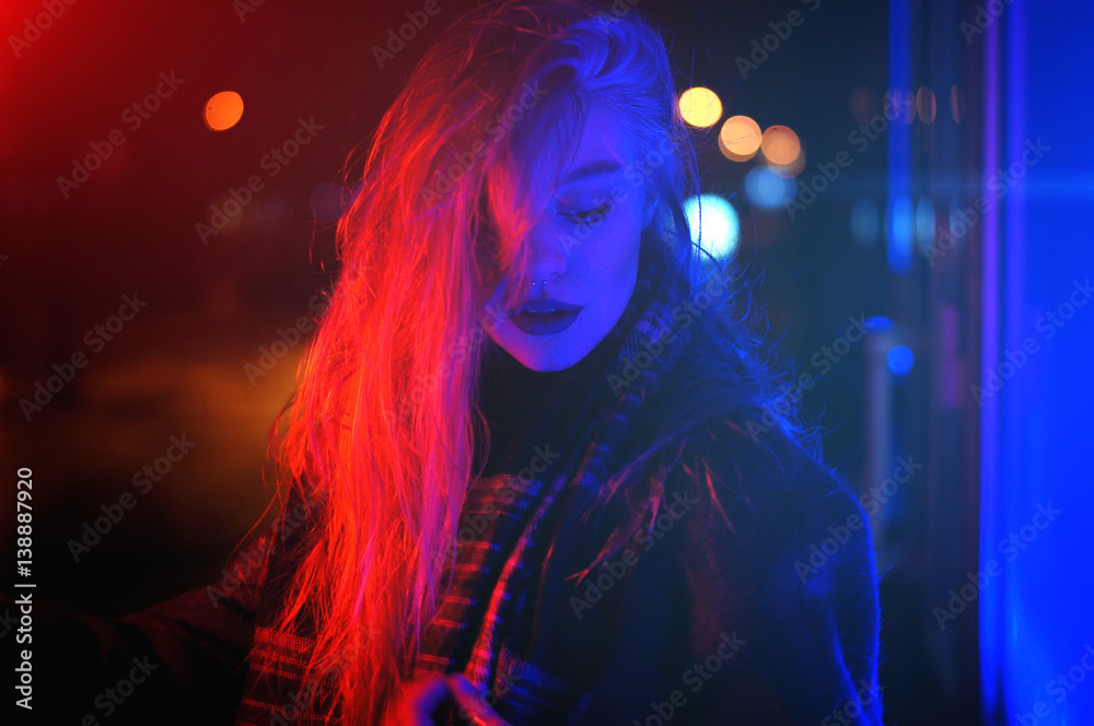 Sexy young beauty woman posing over night city dramatic red and blue ...