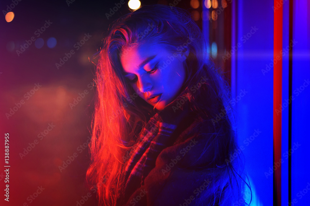 Sexy young beauty woman posing over night city dramatic red and blue ...
