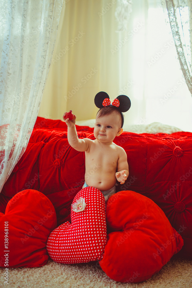 Charming little girl in Minnie Mouse ears raises her hand with toy ...