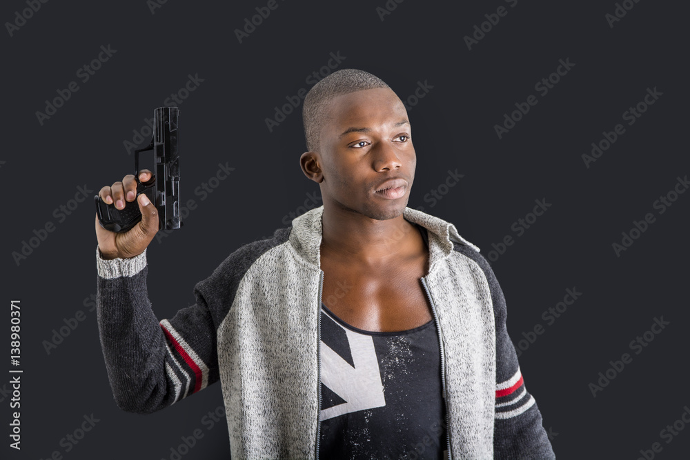 Young handsome black man holding a hand gun, on dark background in ...