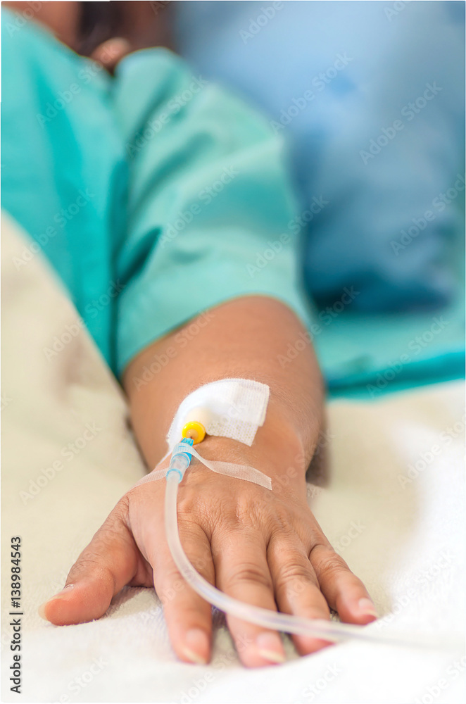 Patient's hand with medicine drip injection, lady on a bed in a ...