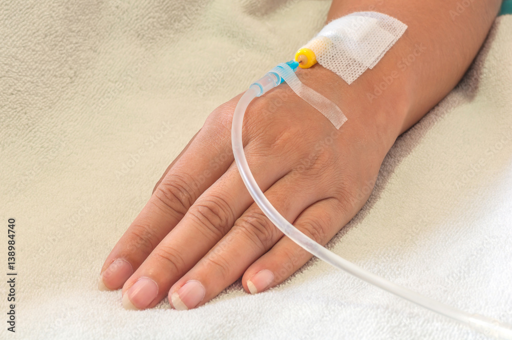 Patient's hand with medicine drip injection, lady on a bed in a ...