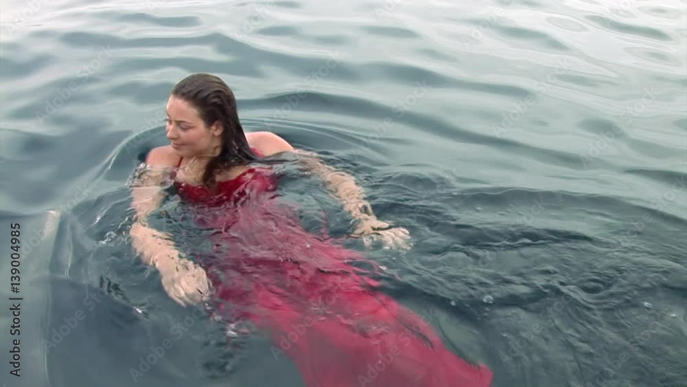 Free diver model in a red dress in water in Red Sea. Filming a movie ...