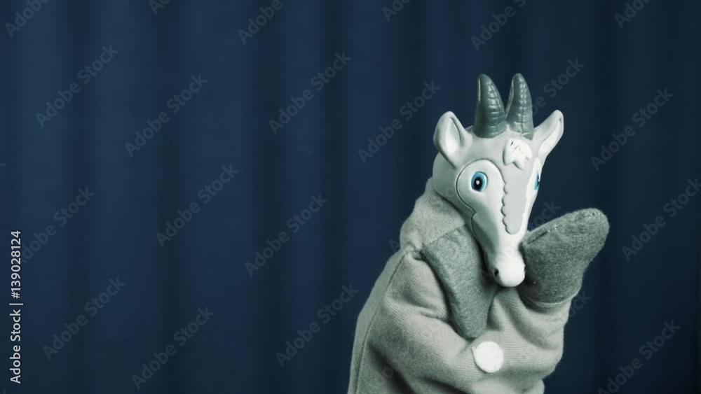 Gray blue eyed goat hand puppet toy appears on scene with blue crease ...