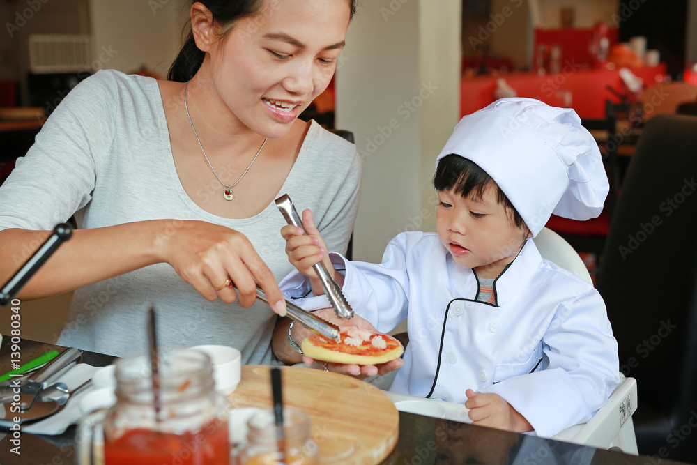 Mother and Kid girl in a suit of the little chef make mini pizza ...