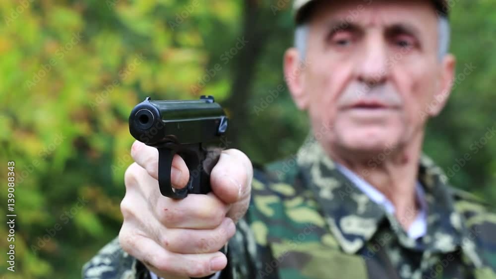 Soldier in military uniform shoots a revolver. Retired officer at ...