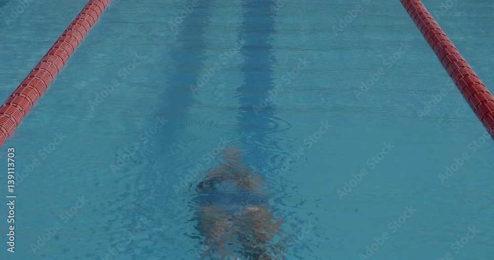 Swimmer pushed of from edge of swimming pool and emerges to do the ...