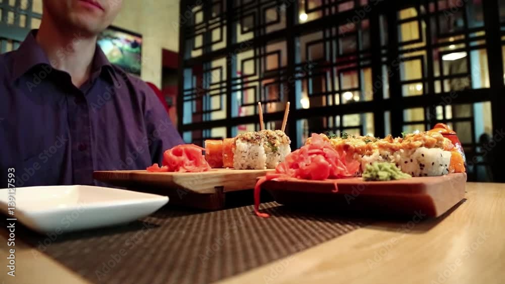 Man sits at the table in restaurant and eats japanese food. Boy in ...
