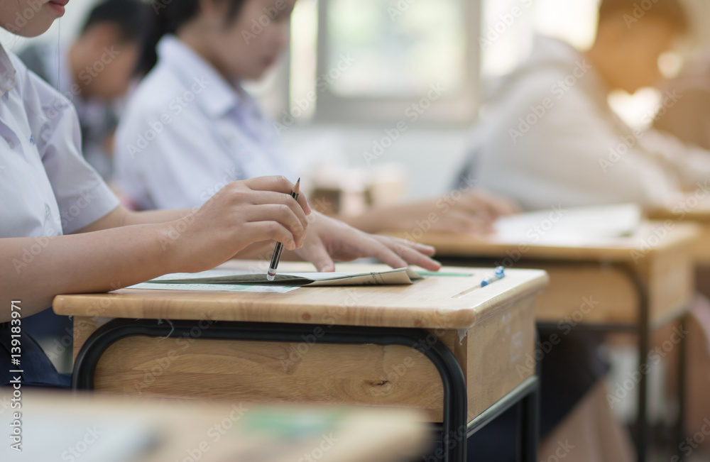 Students hand holding pencil doing examination with blurred abstract ...