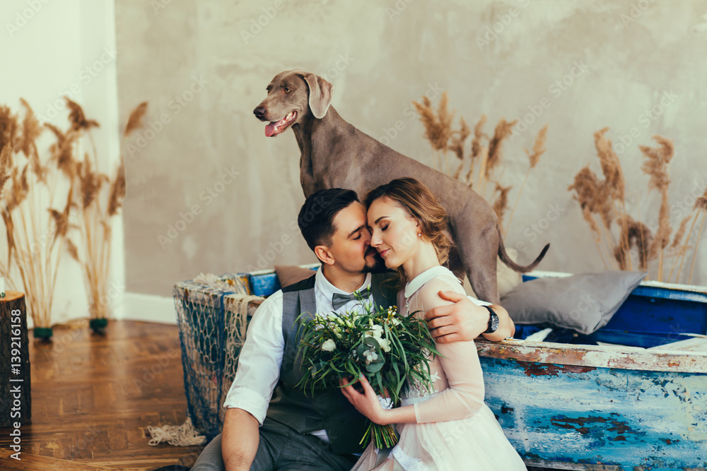 Portrait of kissing newlyweds on the wedding day. couple and a dog in ...