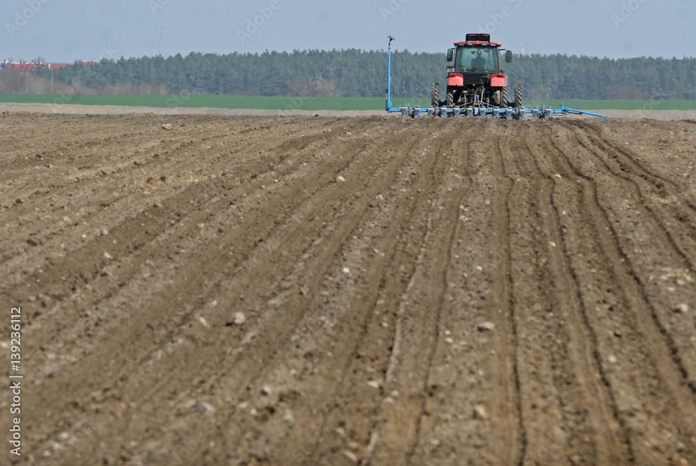 Tractor preparing land for sowing. Tractor with cultivator handles ...