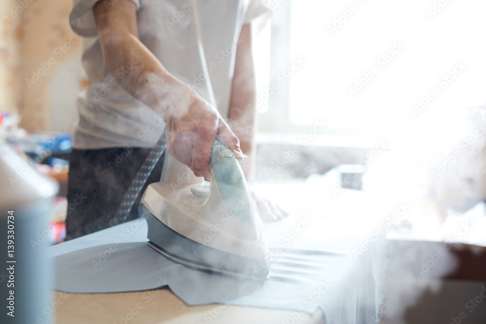 Woman tailor ironing textile with steaming on the iron board before ...