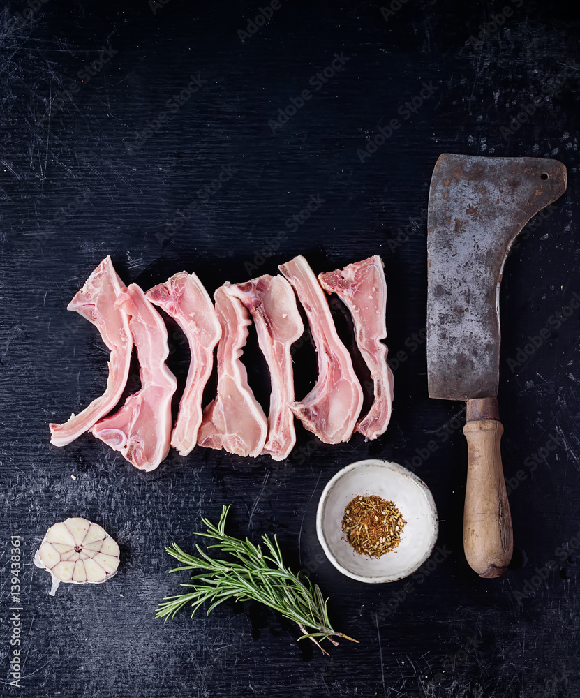 Raw Pork Chops over a rustic black background ready for cooking with ...