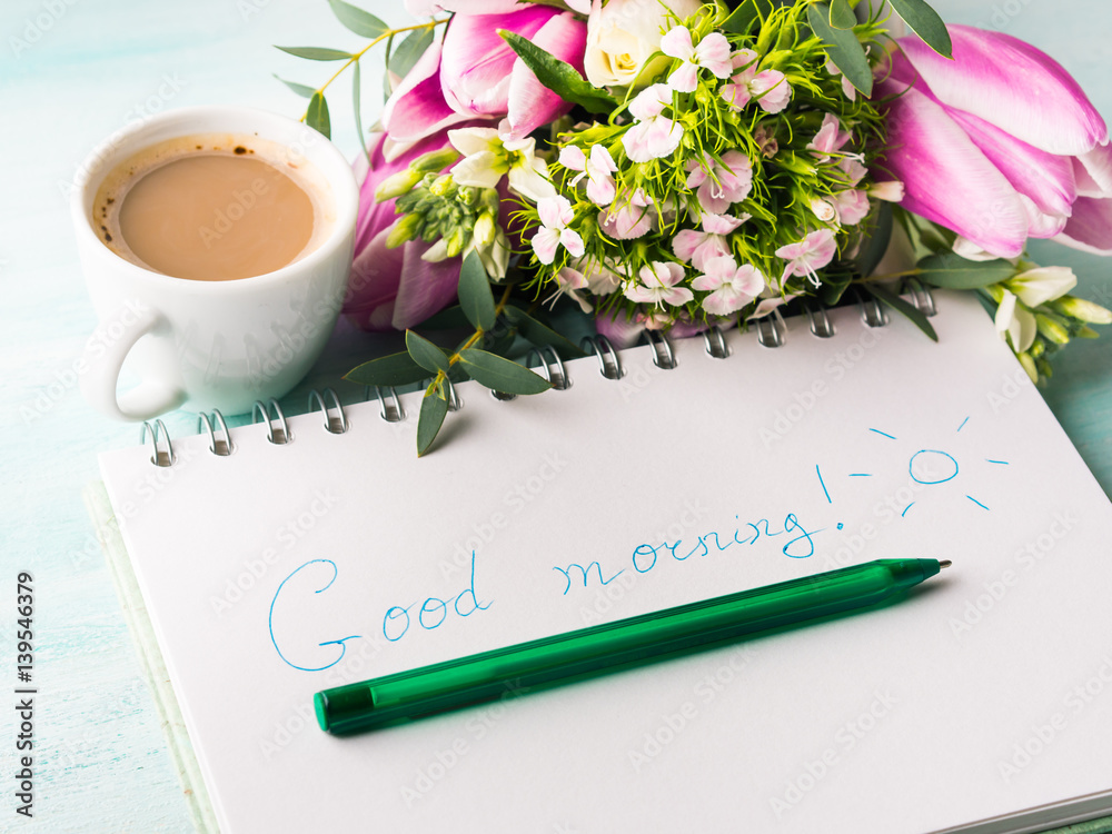 Wishing good morning hand written on notebook page and cup of coffee ...