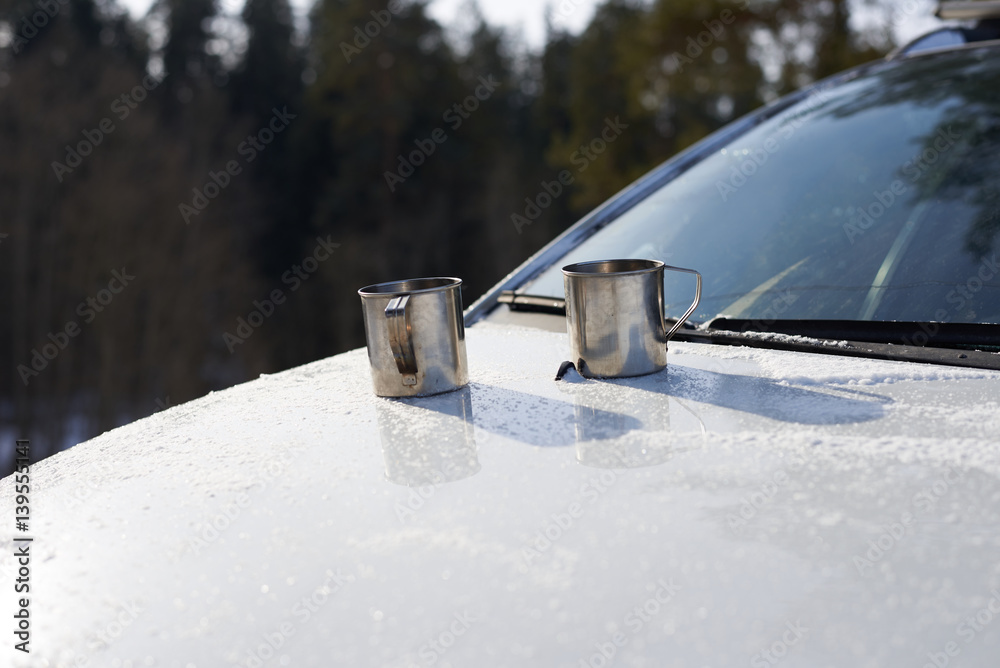Auto travel concept. Couple cups of tea on the hood. Part of car with ...