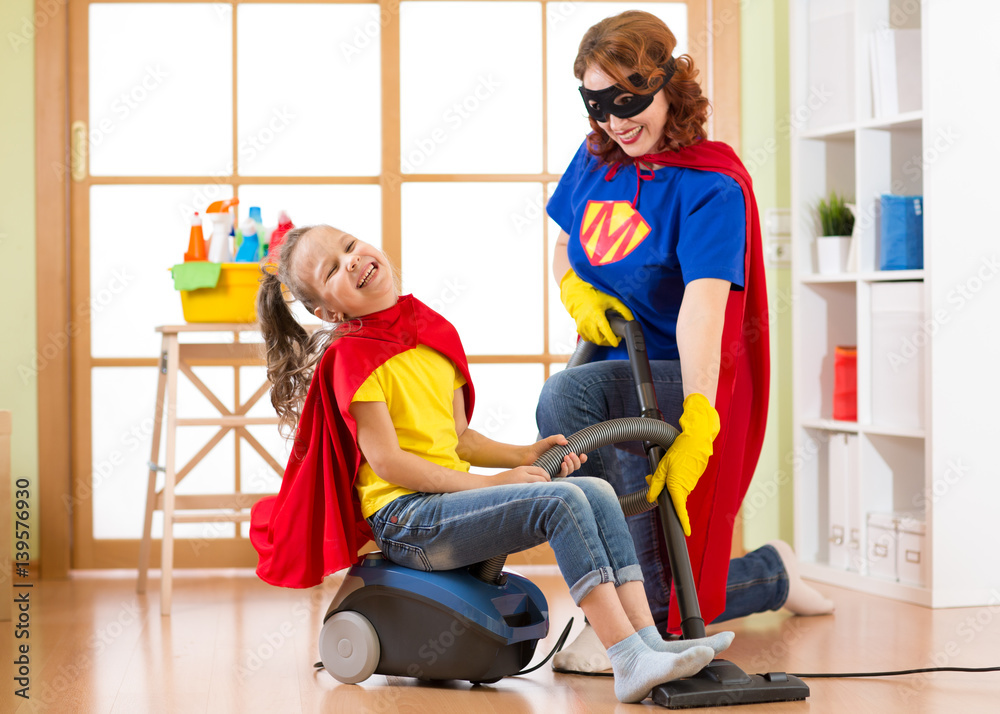 Superhero kid girl and her mother doing laundry together in the living ...