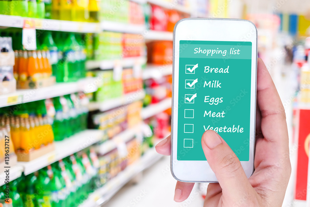 Hand holding smart phone with grocery shopping check list application ...