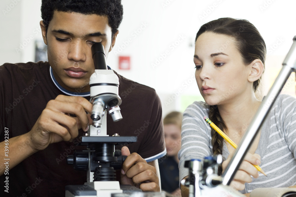 Student looking through microscope in science class Stock Photo | Adobe ...