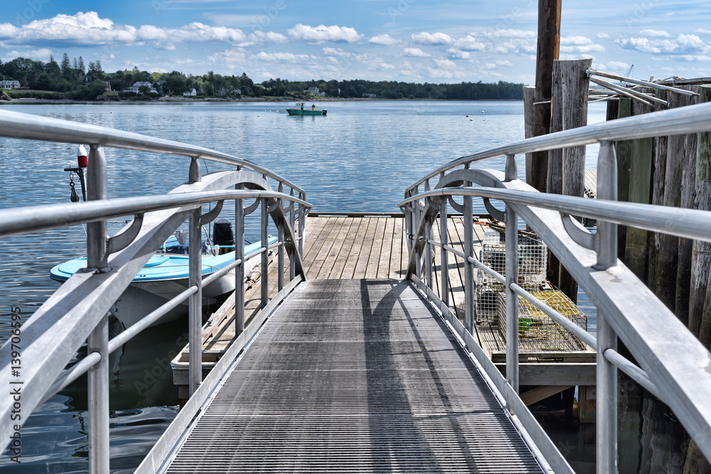 Handrails leading down to a floating dock with a lobster boat in ...