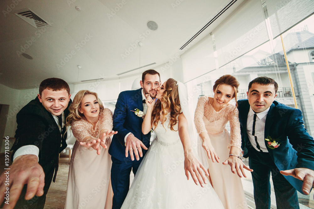 Newlyweds and their friends reach out hands to the camera while they ...