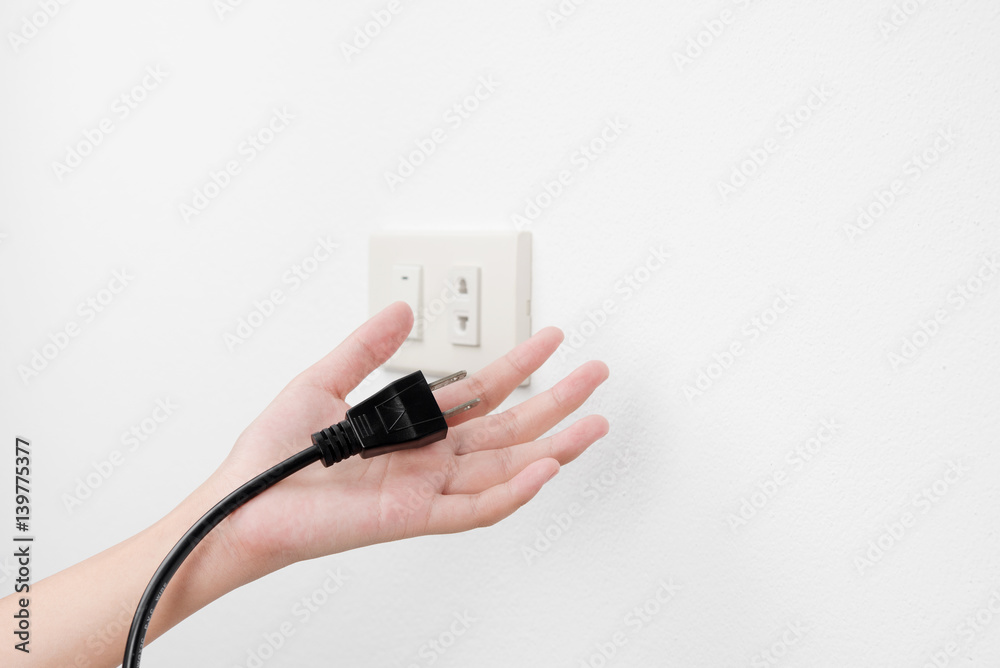 Plug on hand or unplug and outlet on white wall background , electric ...