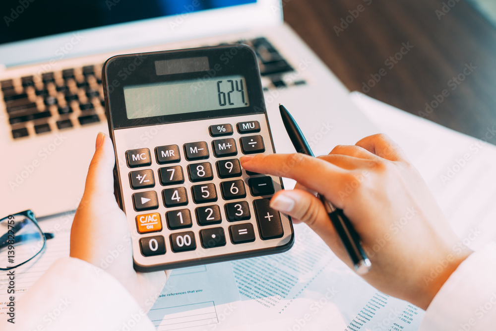 Female hands holding pen and using calculator Stock Photo | Adobe Stock