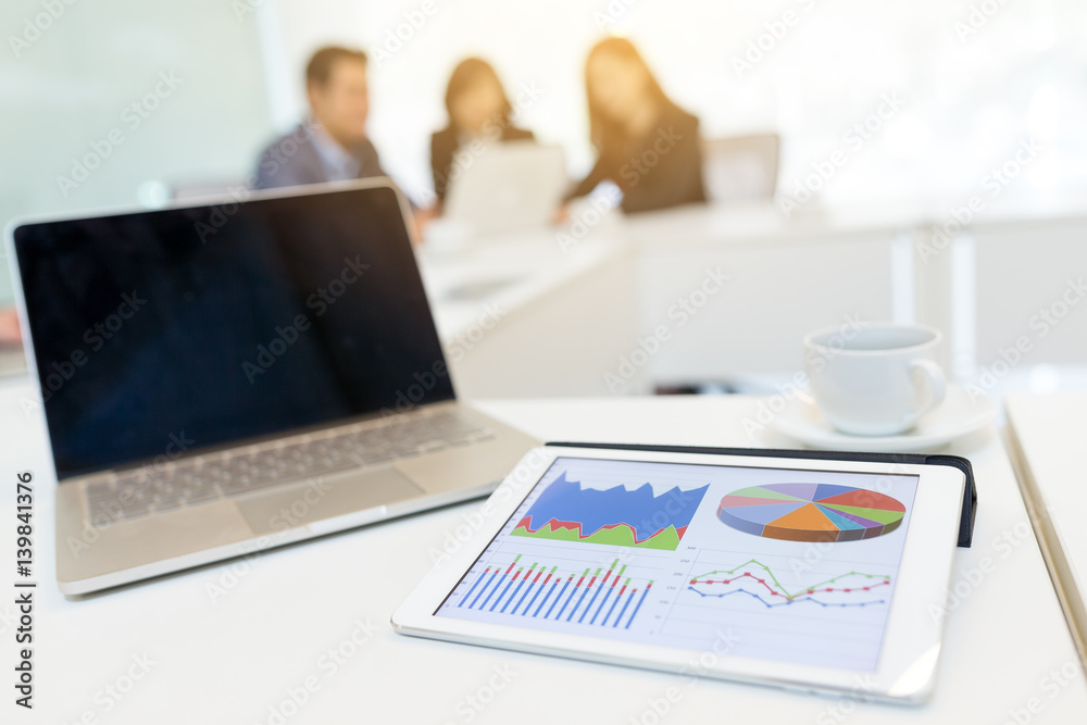 Digital tablet showing data chart on screen and blank screen of laptop ...