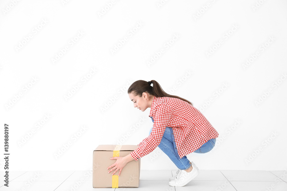 Posture concept. Young woman lifting heavy cardboard box against white ...