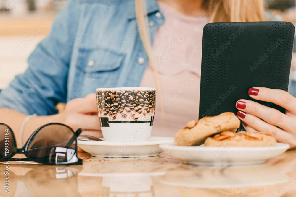 Cute girl reading e-book one in the cafe and drinking coffee with ...