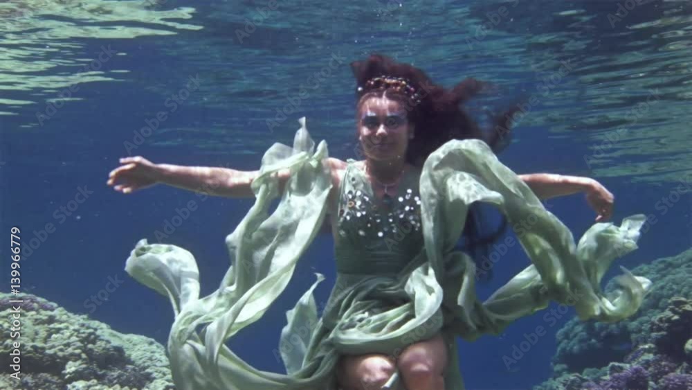 Young girl model underwater poses for camera on background of corals in ...