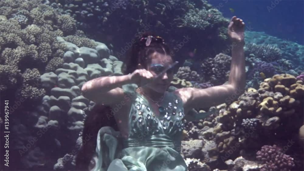 Underwater model free diver poses for camera on background of corals in ...