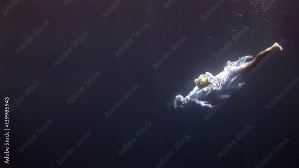 Young girl model underwater white angel costume on blue background in ...