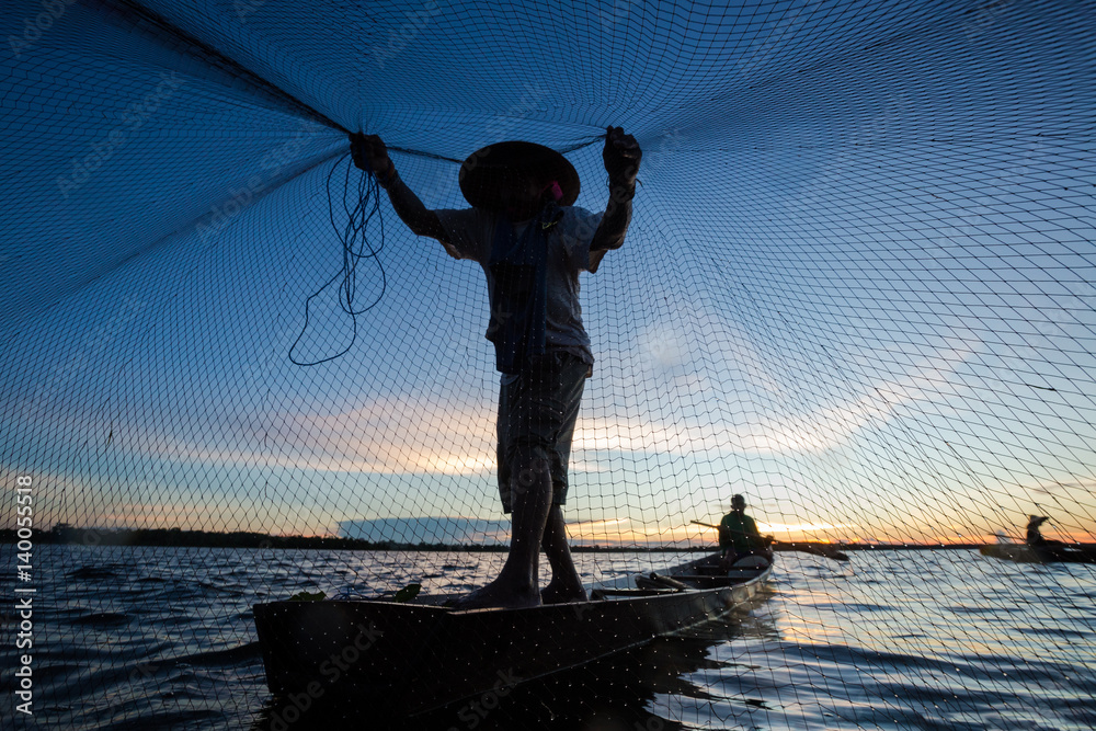 Thai fisherman on wooden boat casting a net for catching freshwater ...