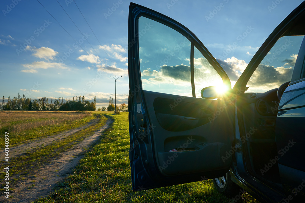 Passenger car with the door open on a meadow beside a dirt road in an ...